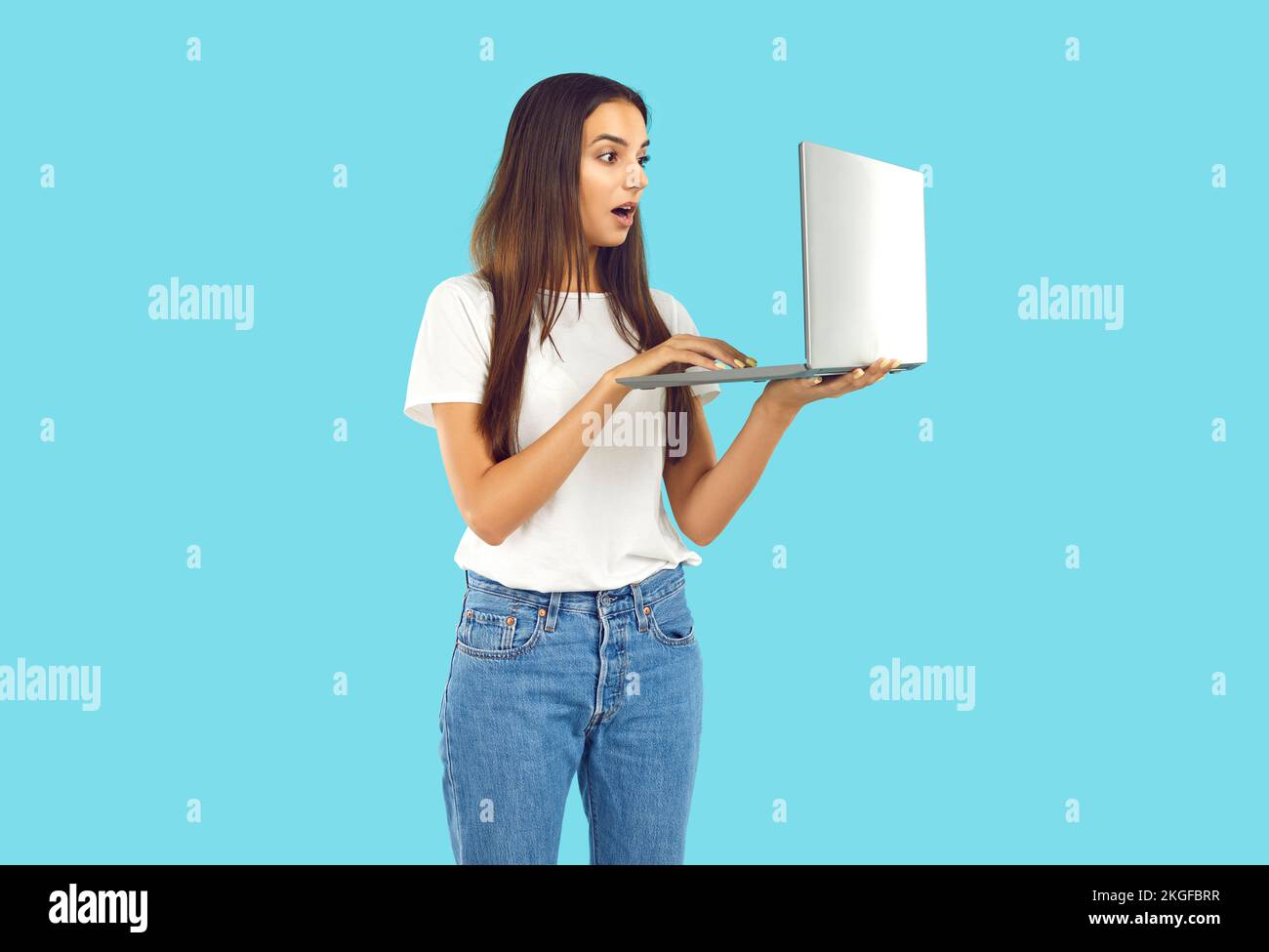 Shocked woman with surprised look looks at laptop screen and sees ...