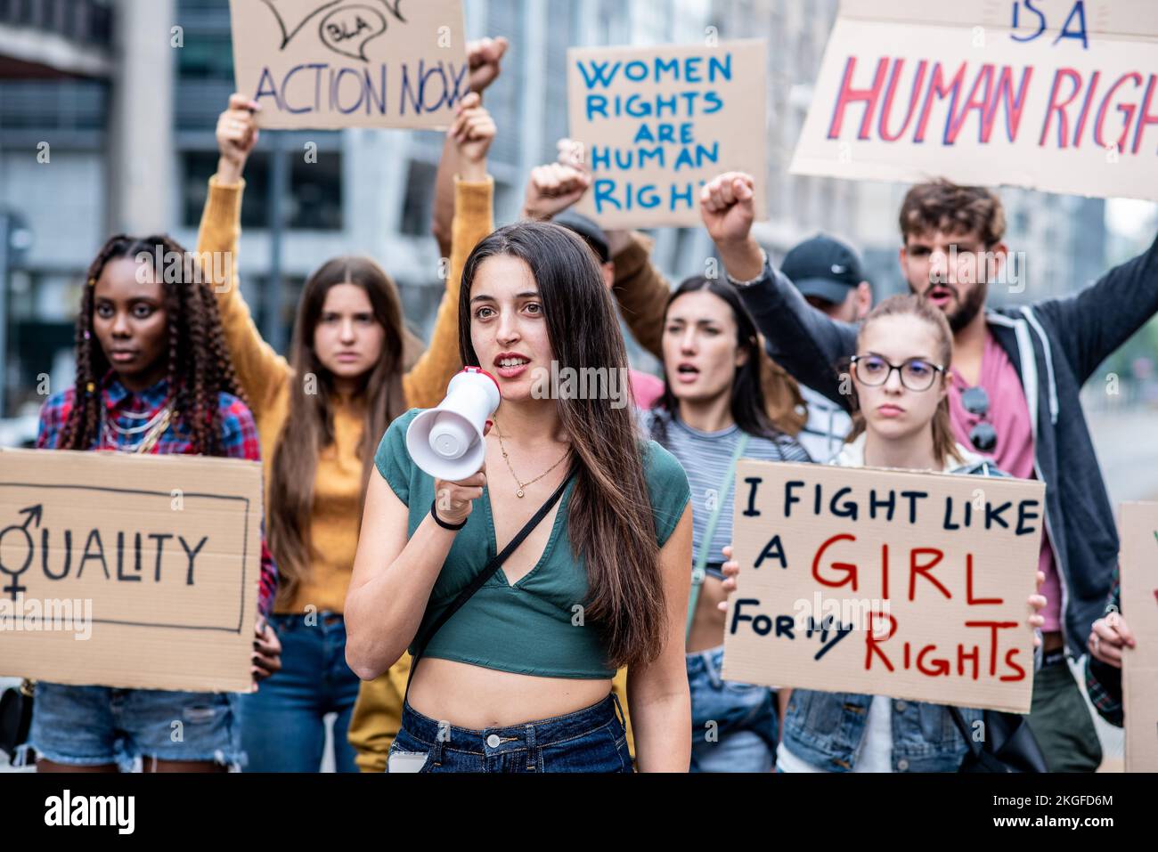 Young woman with megaphone leading a multiracial group of people in a ... Young woman with megaphone leading a multiracial group of people in a ...