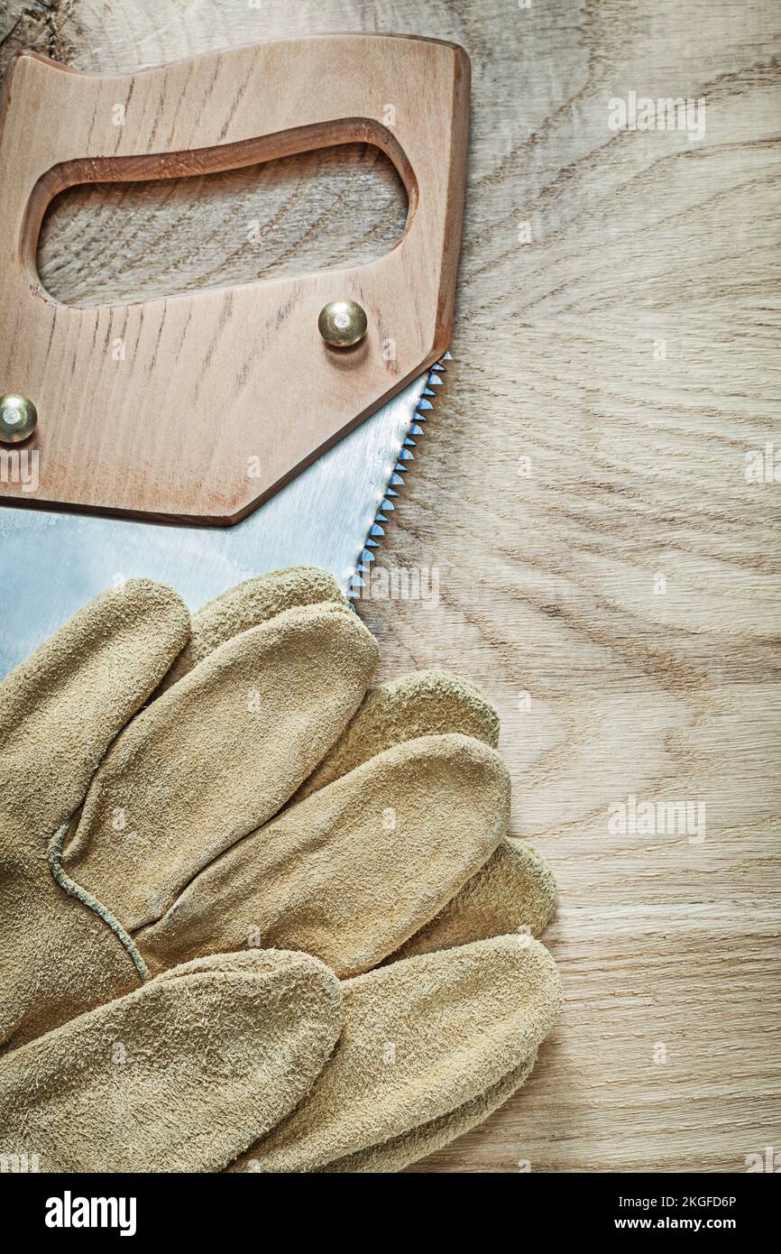 Vertical image of safety gloves stainless hacksaw on wooden board ...