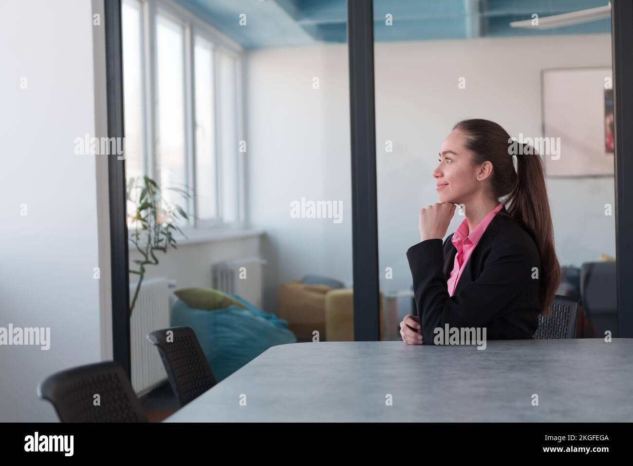 Successful young female leader in a suit with a pink shirt sitting in a ...