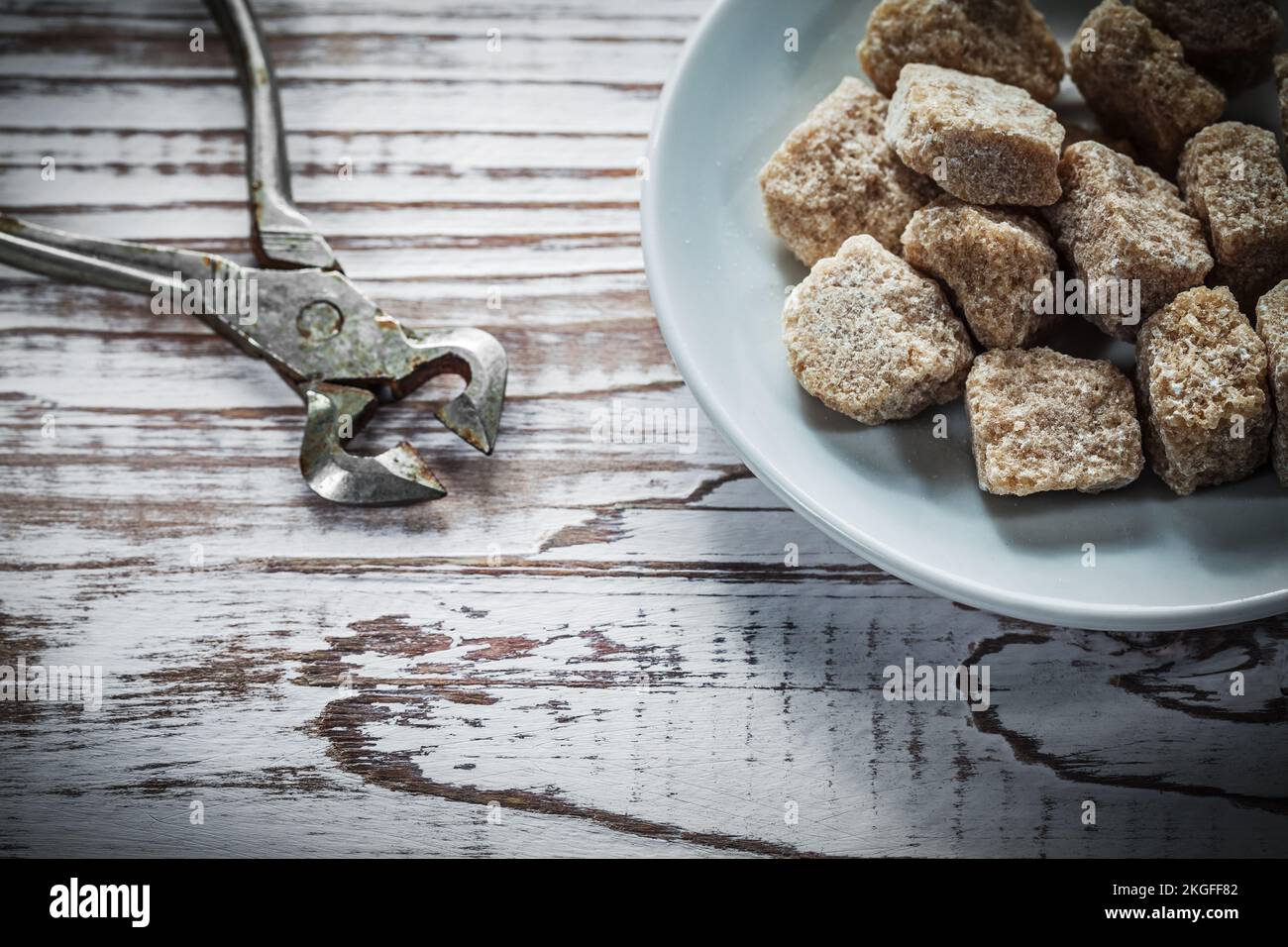 Vintage brown sugar pliers saucer on wooden board Stock Photo - Alamy