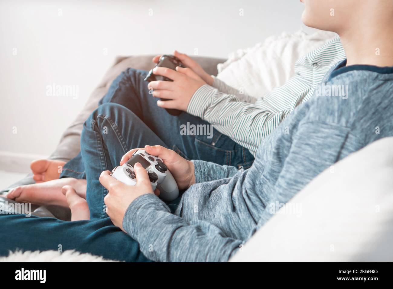 Cropped photo of two teenage boys sitting at home, holding gaming ...