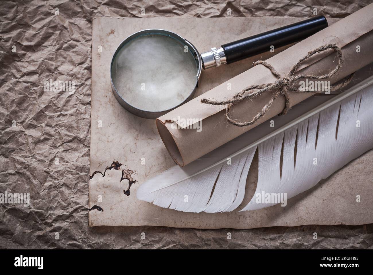 Vintage sheet feather loupe rolled document on messy crumpled paper ...