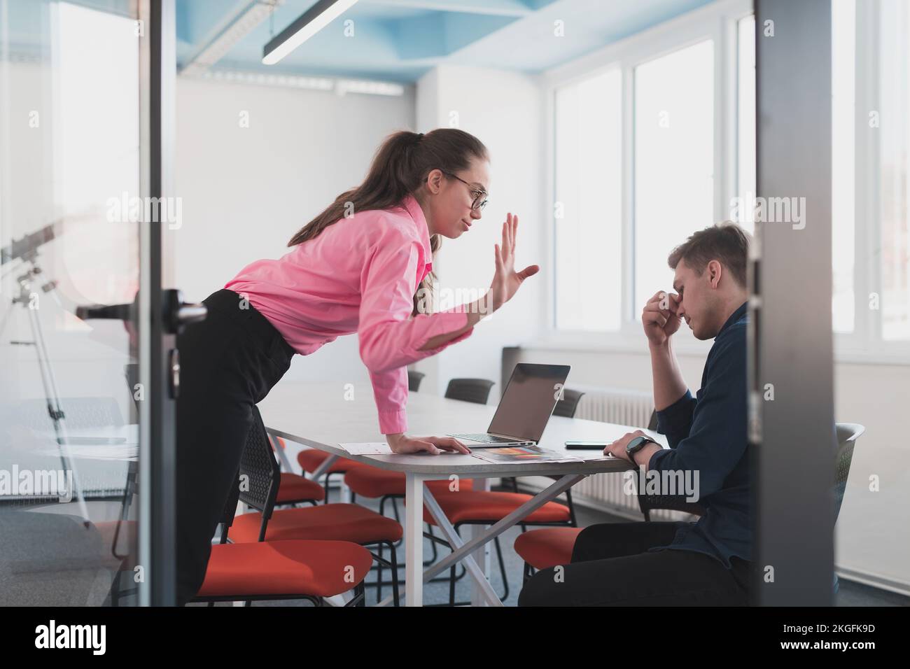 Emotional couple of young colleagues arguing in modern office. Business ...