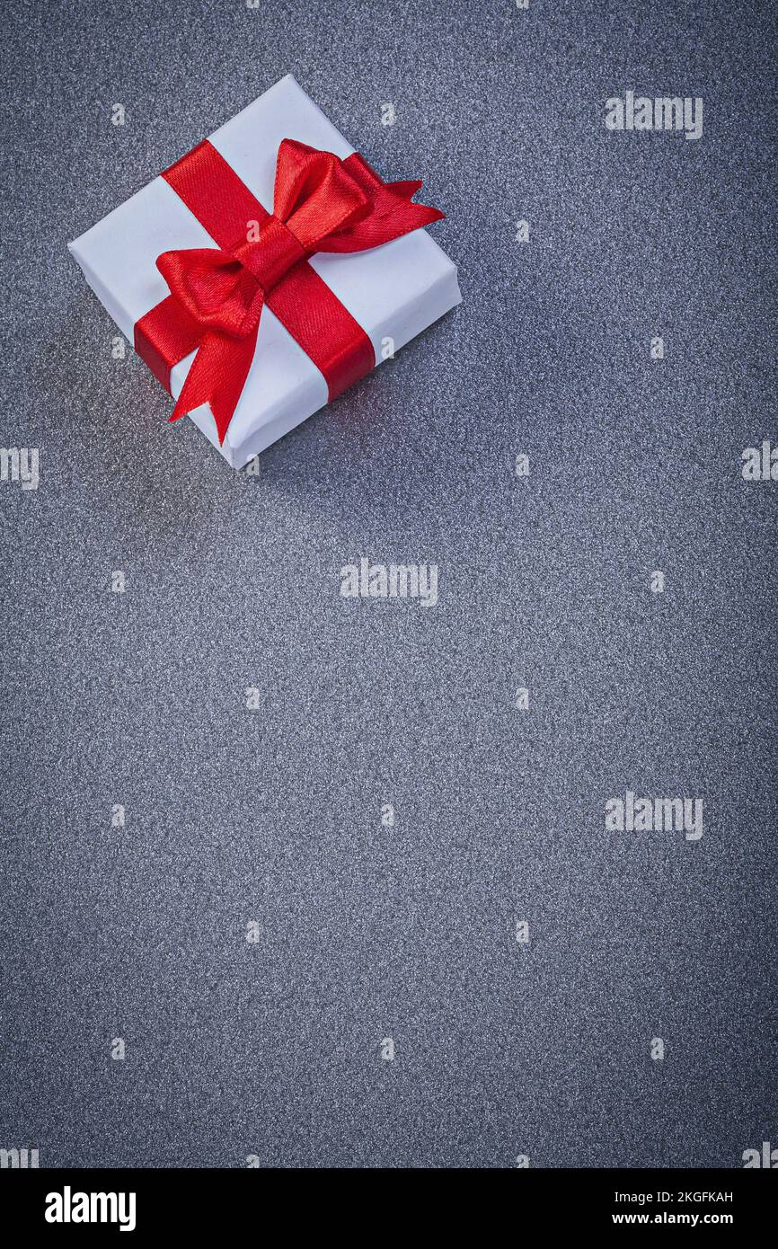 White boxed present with red knot on grey surface copyspace holidays ...