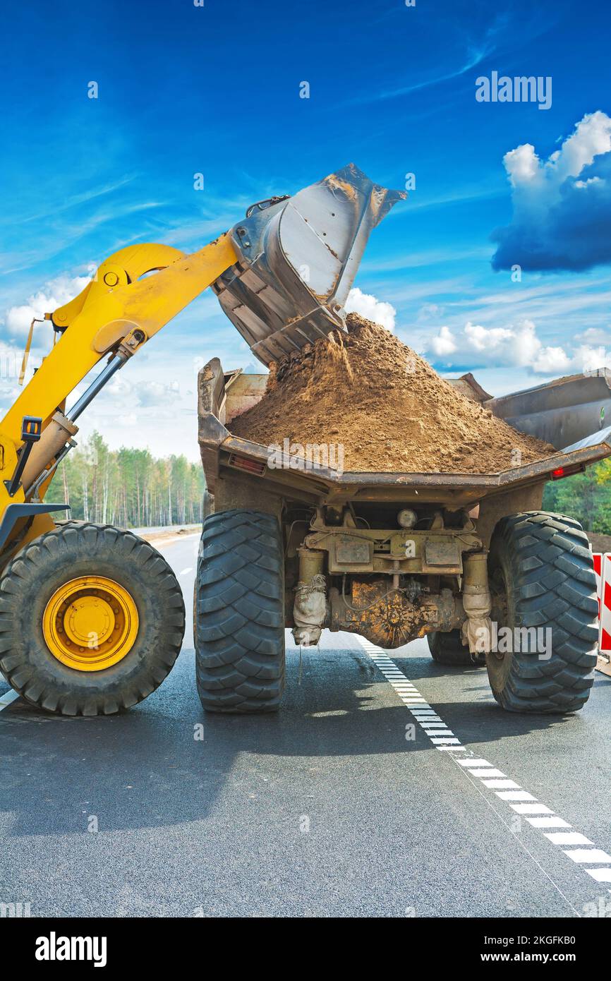 wheel loadder loadding ground on tipper Stock Photo - Alamy
