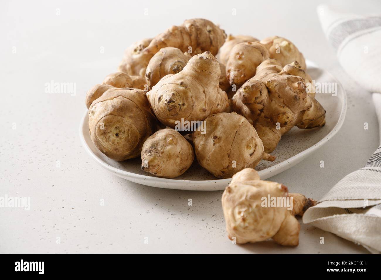 Jerusalem artichoke root , sunchoke in white plate and on white ...