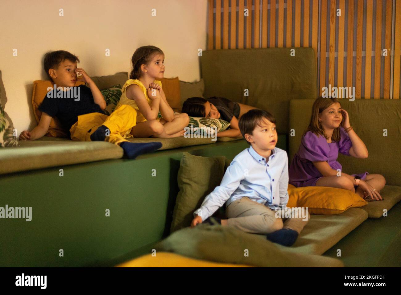 Little boys and girls look shocked and surprised watching movie in home ...