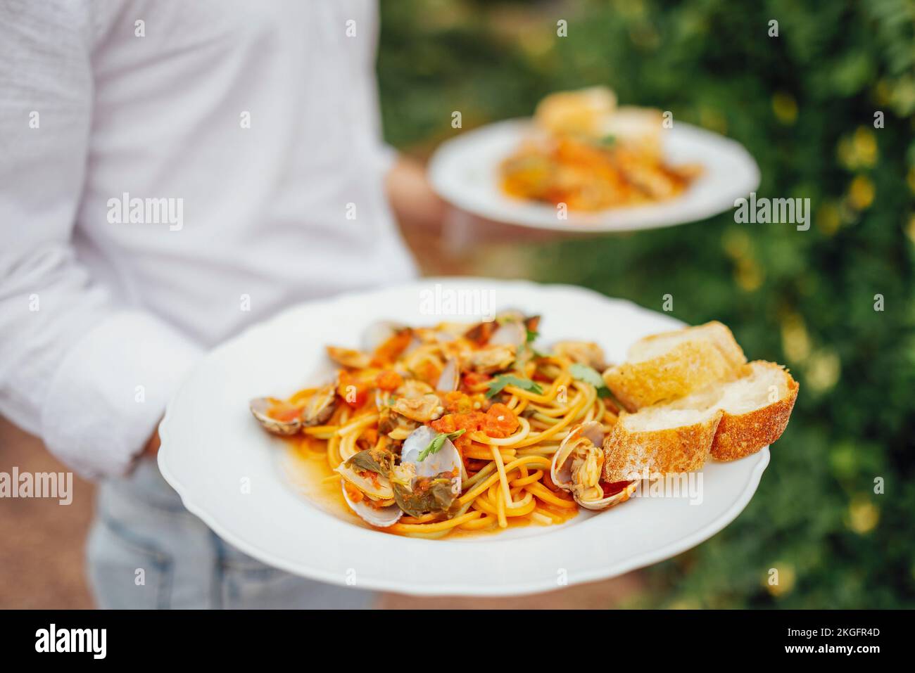 Seafood Spaghetti with seashells, prawns, squids hands of the waiter on ...