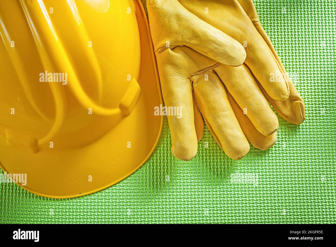 Yellow building helmet safety gloves on green background construction ...