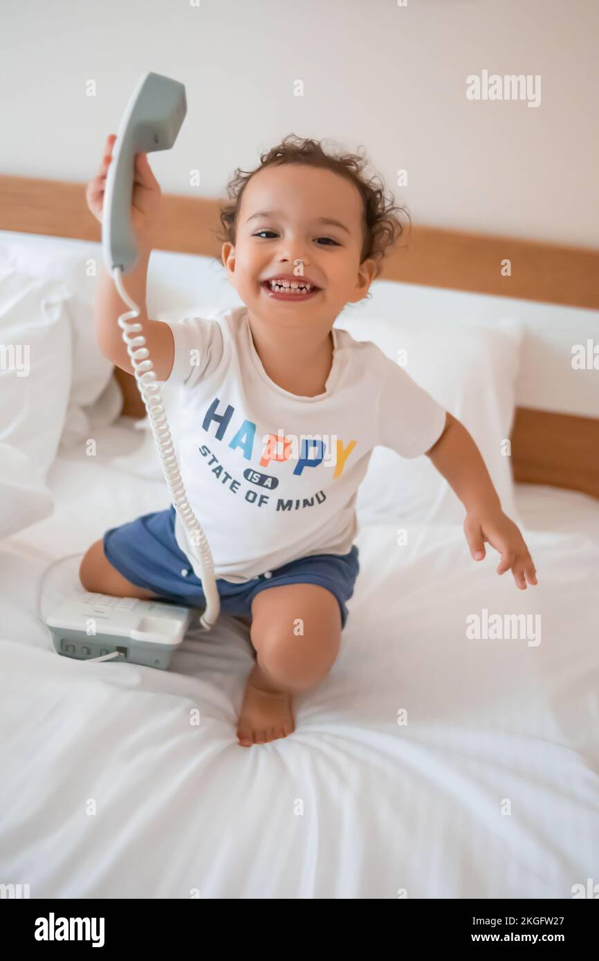 Happy kid calling on a push-button telephone in hotel room Stock Photo ...