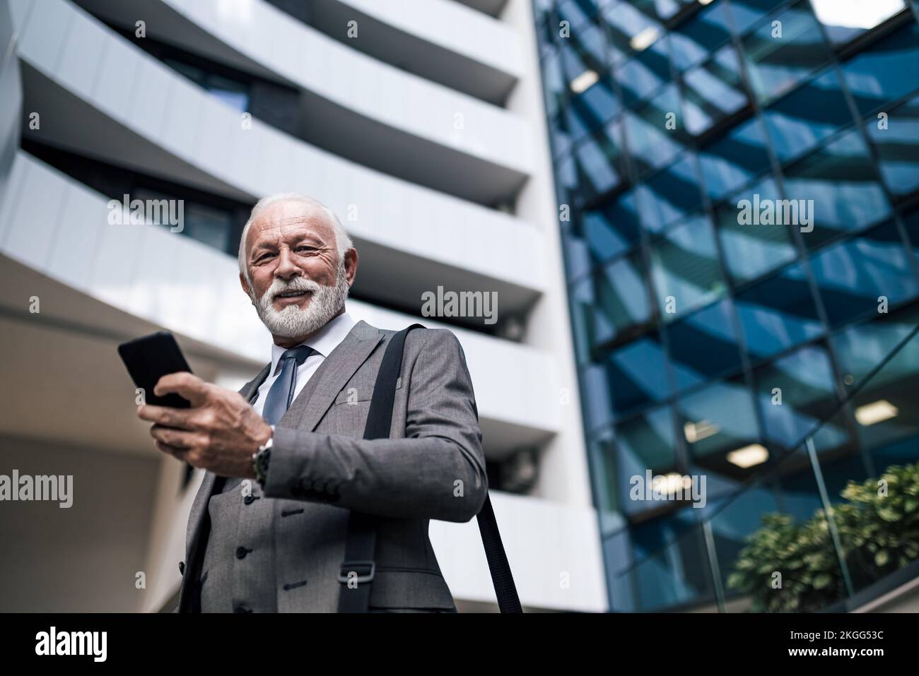 Low angle portrait of senior business manager using smart phone ...