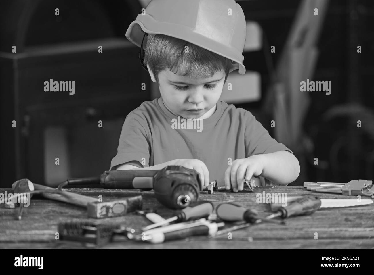 Busy kid playing with metal bolts. Little worker sitting at table with ...