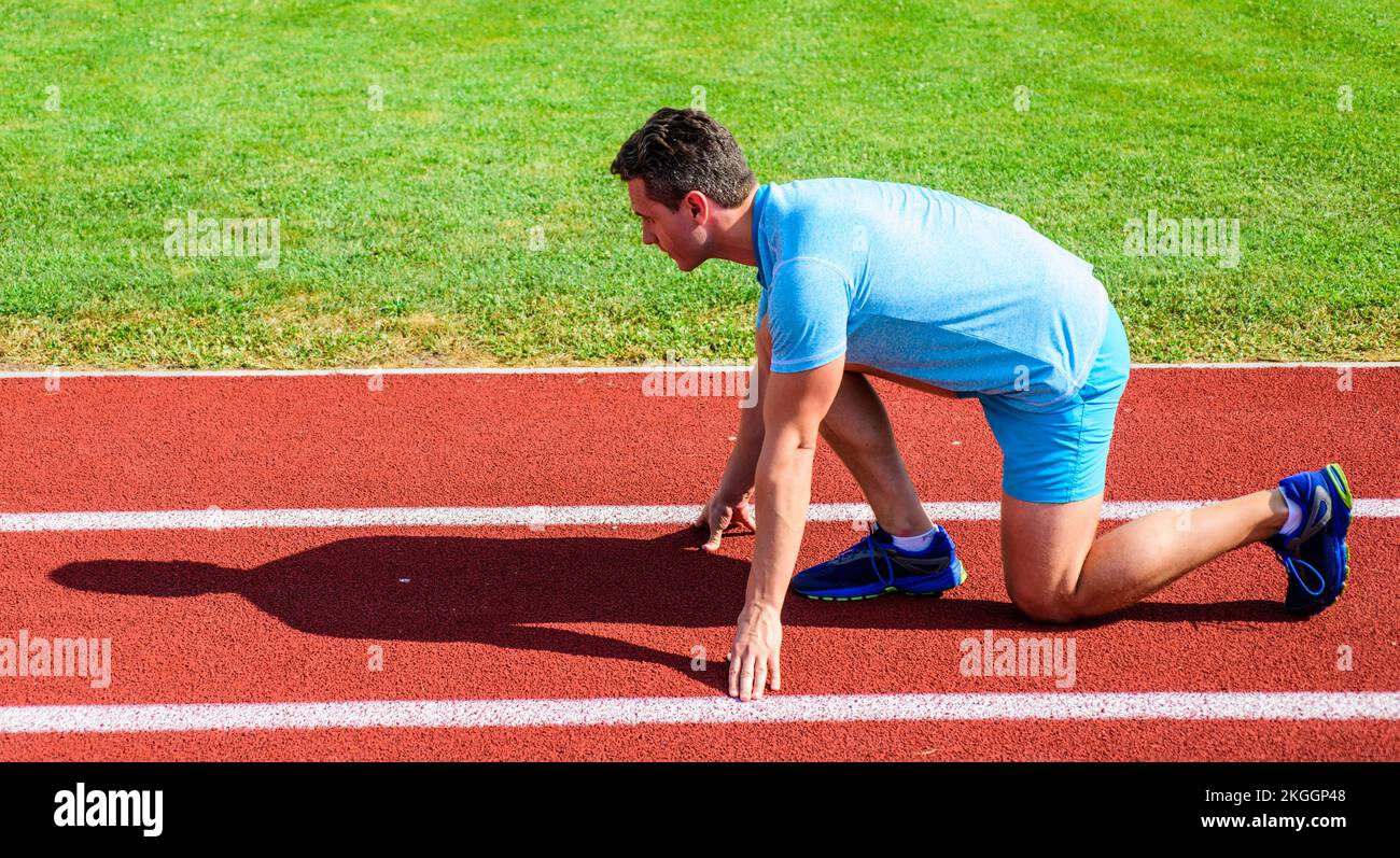 Man athlete runner stand low start position stadium path sunny day ...