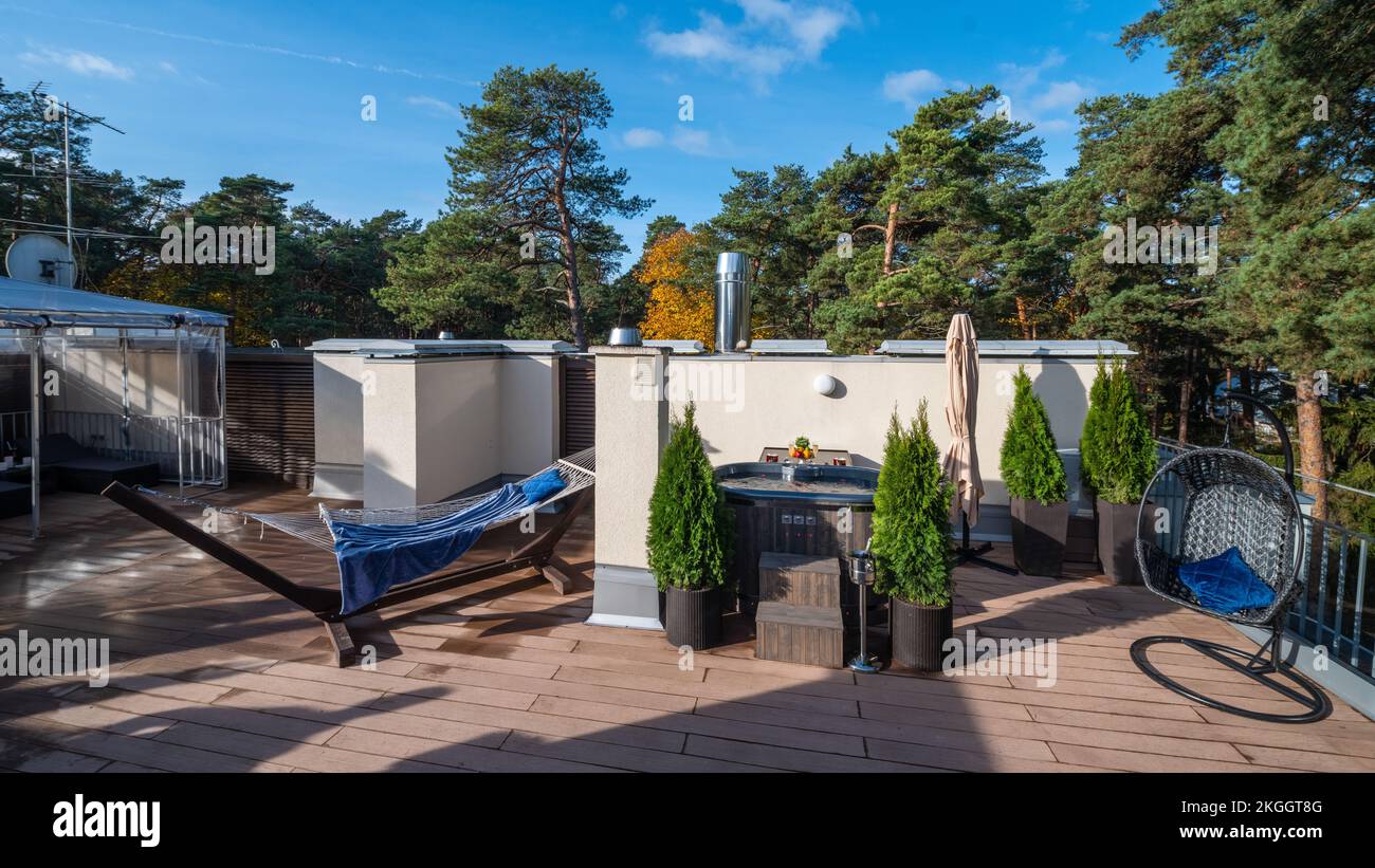 View of the outdoor terrace. Hammock with bath tub and rattan chair ...