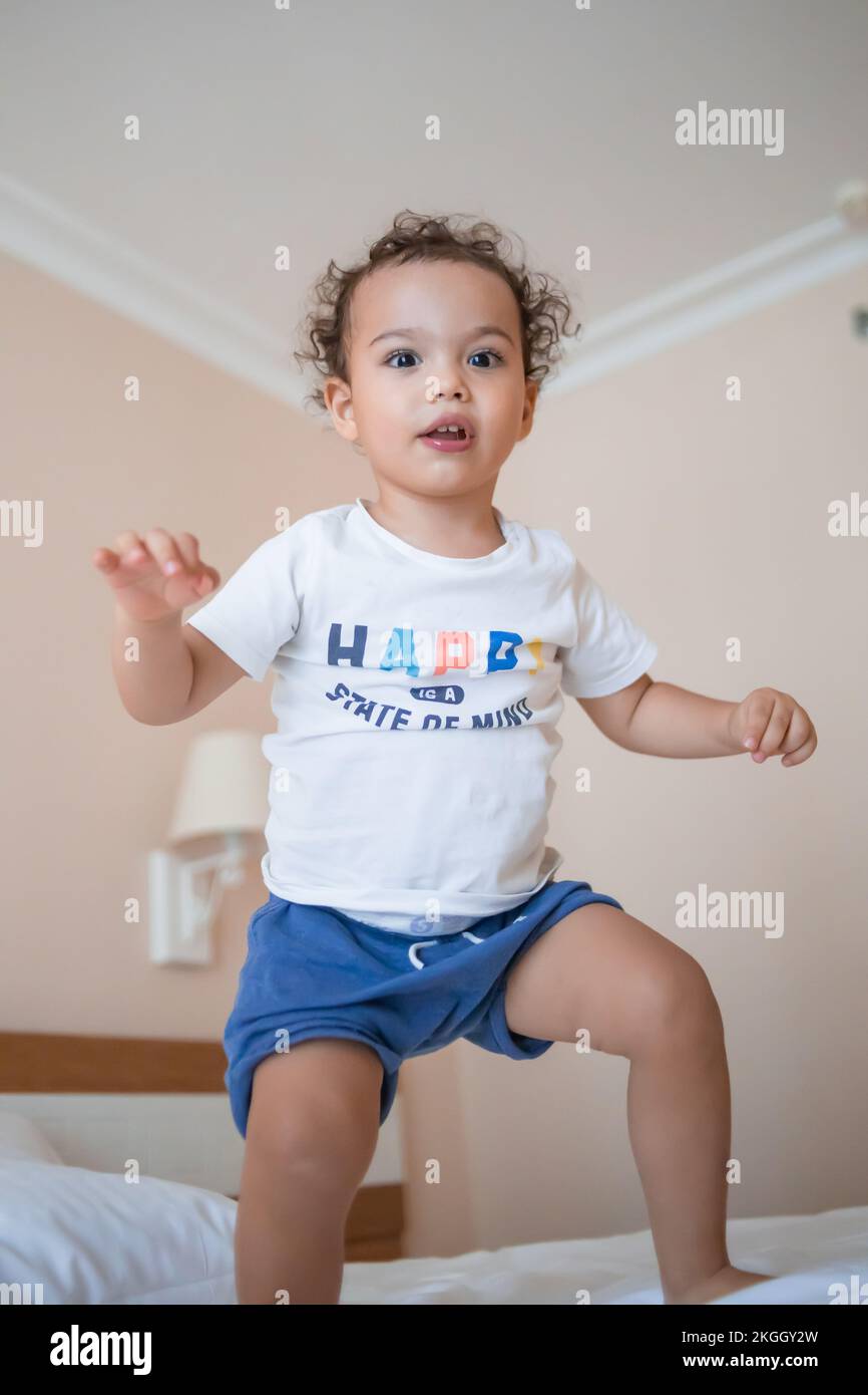 Funny happy kid jumping on parents bed in master bedroom Stock Photo ...