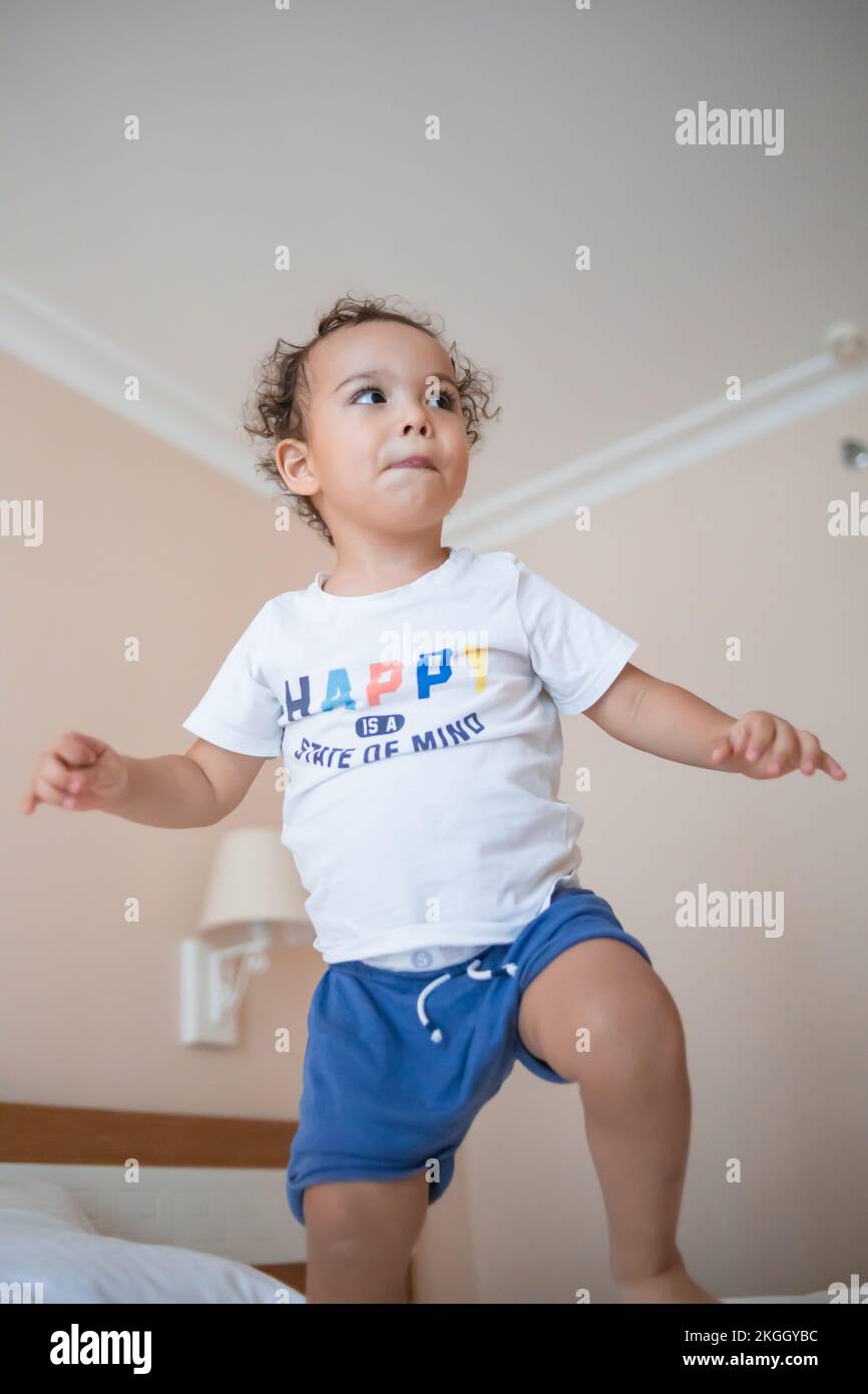 Funny happy kid jumping on parents bed in master bedroom Stock Photo ...