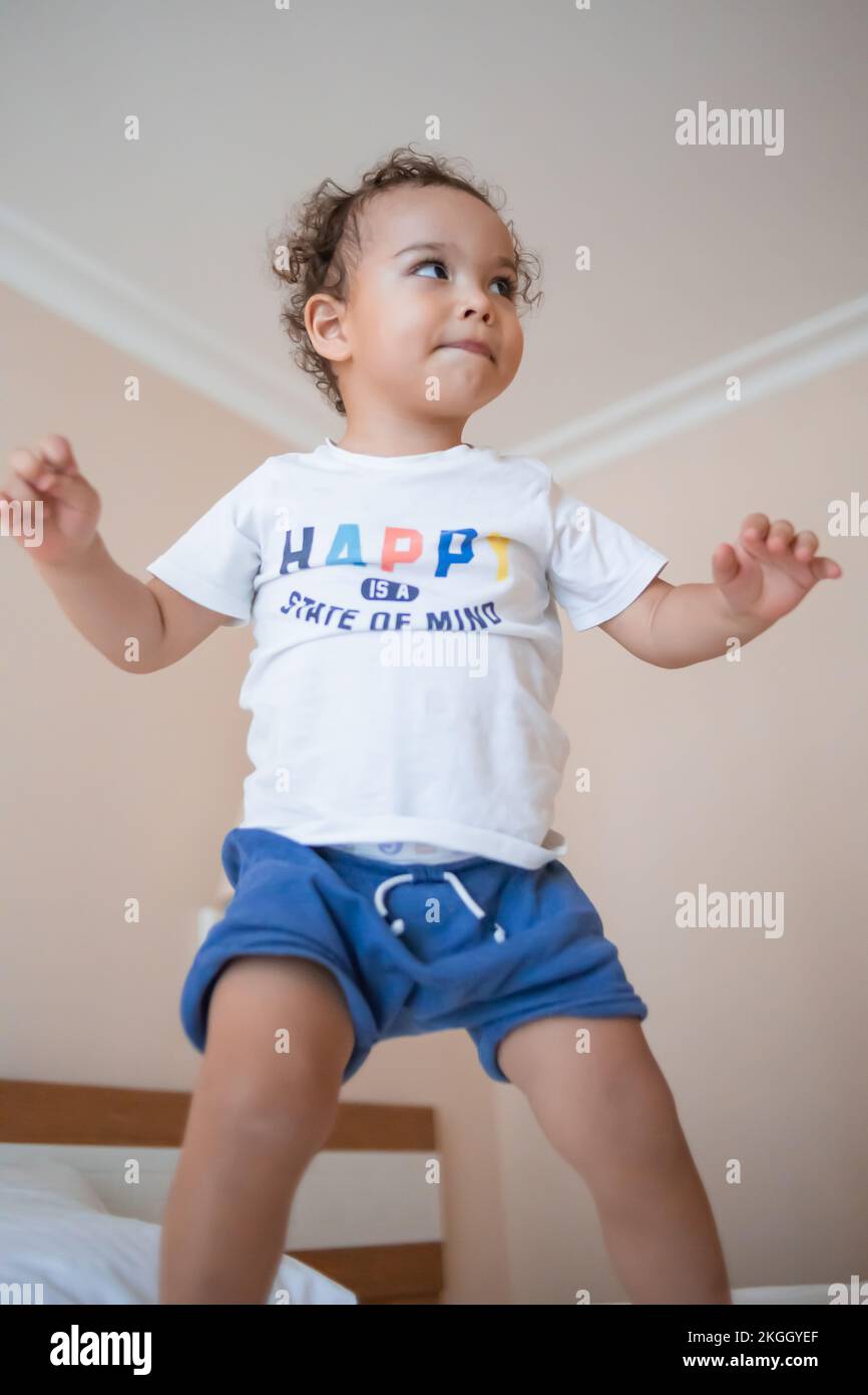 Funny happy kid jumping on parents bed in master bedroom Stock Photo ...