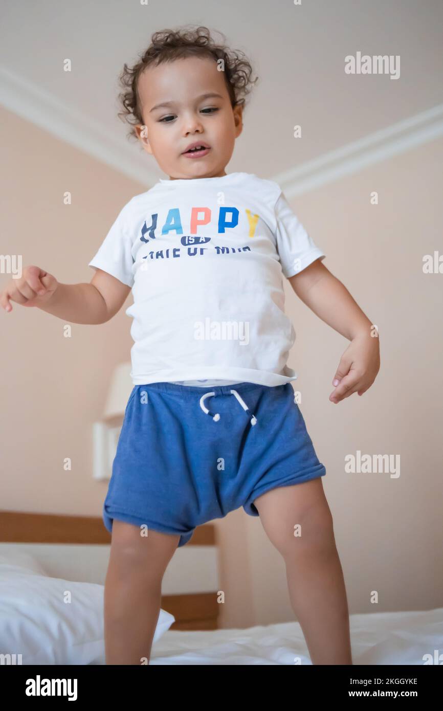 Funny happy kid jumping on parents bed in master bedroom Stock Photo ...