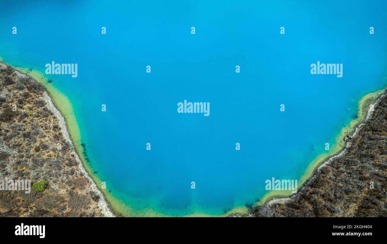 An aerial of the separation of the blue blooming Haba lake and a brown ...