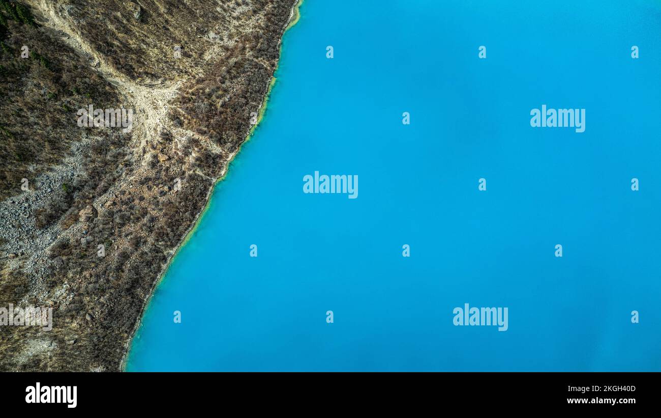 An aerial of the separation of the blue Haba lake and a brown grassland ...