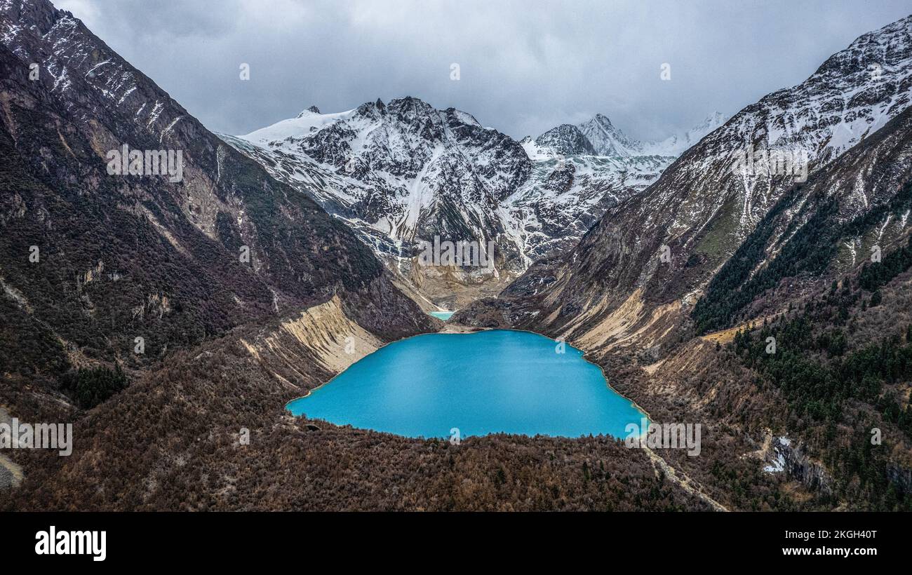 An aerial of the blue Haba lake with the background of snowy rocky ...