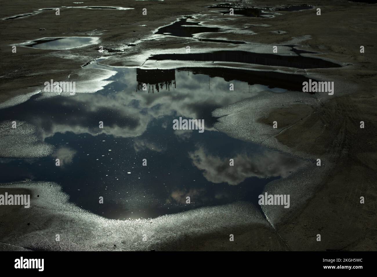 Puddle on pavement. After rain. Road in pits. Reflection of sky in ...