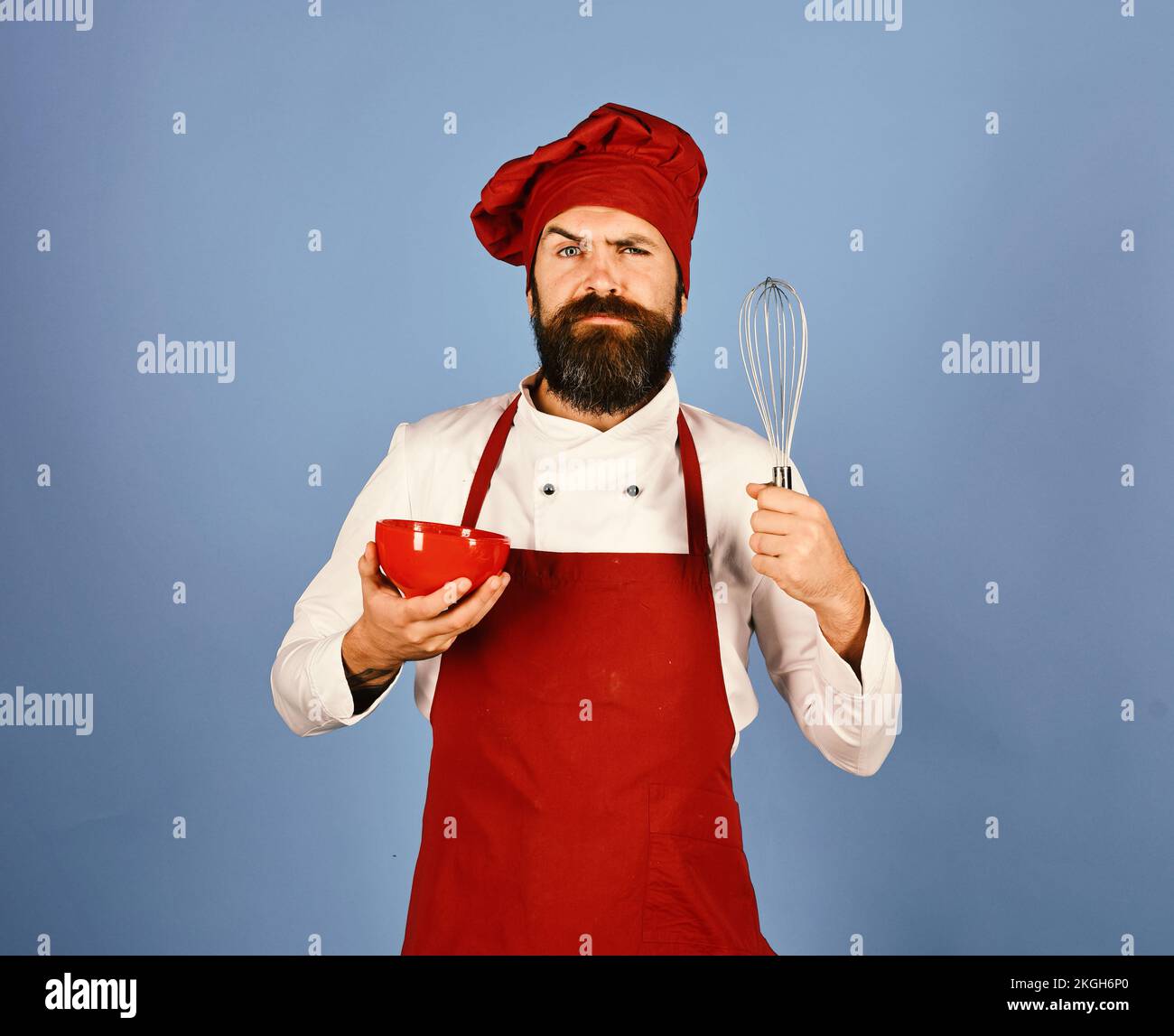 Cook with confused face in burgundy uniform uses kitchenware Stock ...
