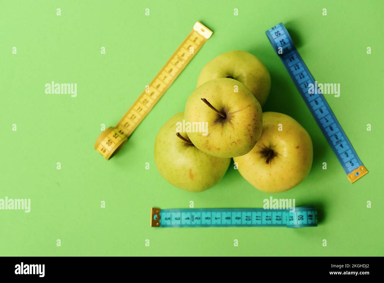 Apples near measuring tape rolls on green background, top view Stock ...