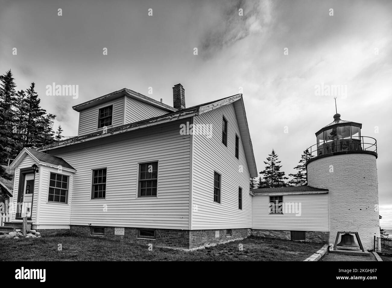 A grayscale of a Lighthouse with trees beside under rainy clouds in ...