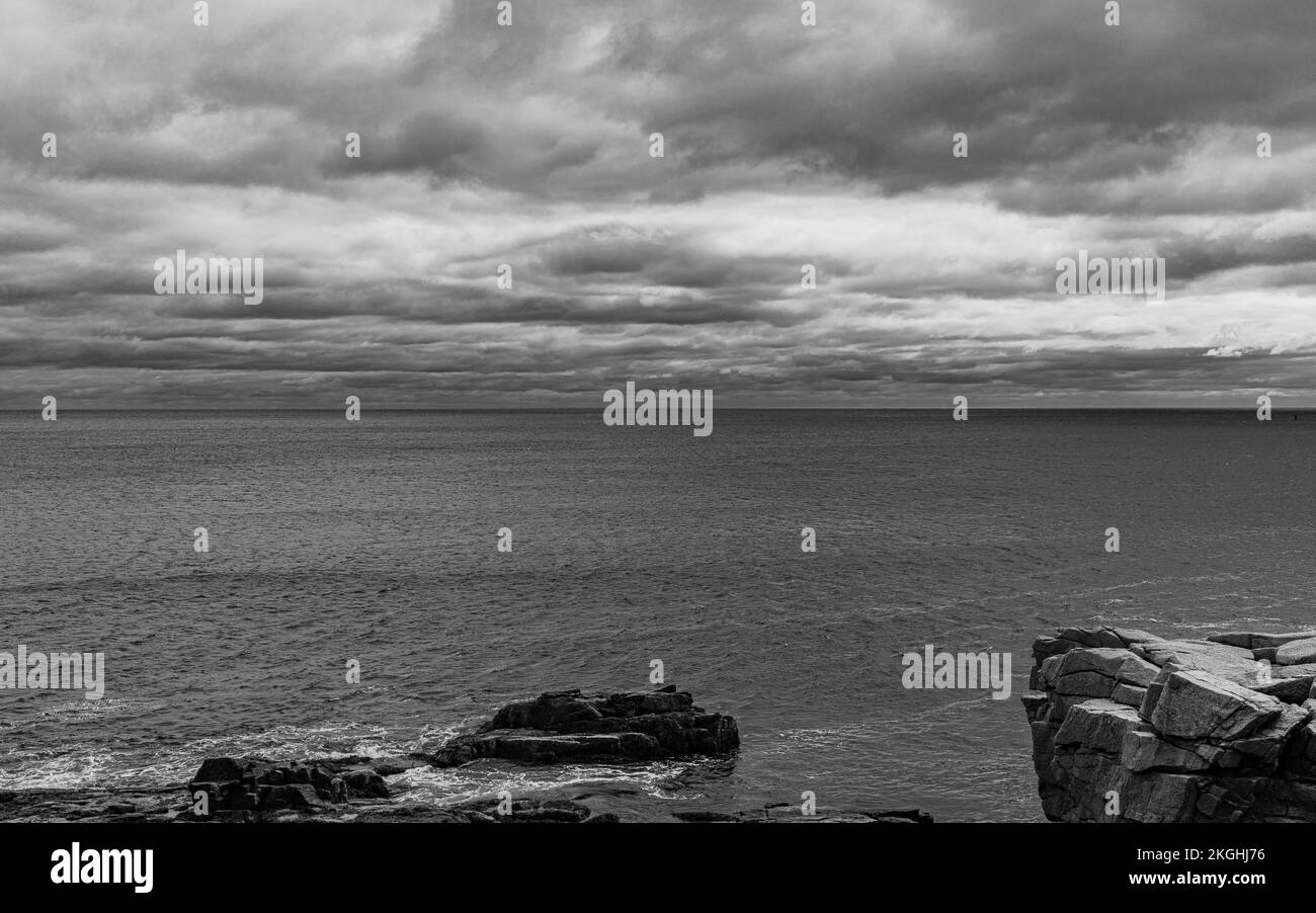 A landscape of a rocky coast by the sea with gray cloudy sky on the ...