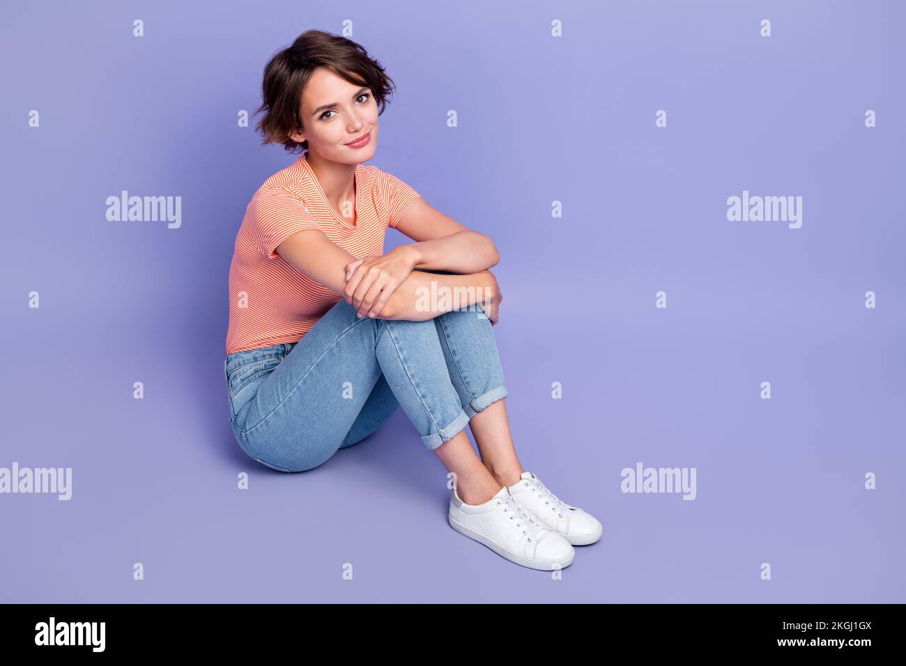 Full length photo of adorable young woman sit floor embrace knees ...