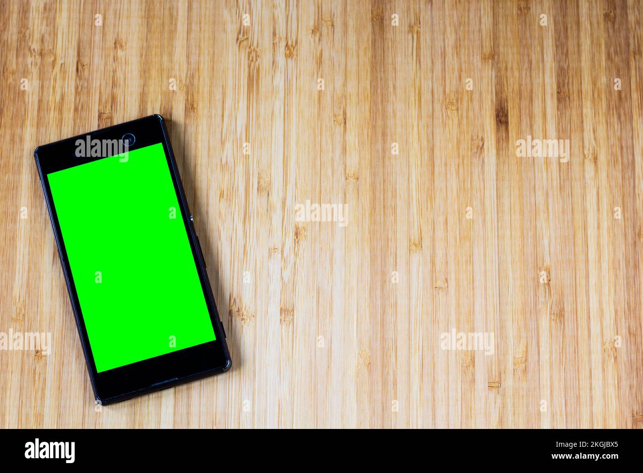 smartphone phone with green screen on wooden table Stock Photo - Alamy