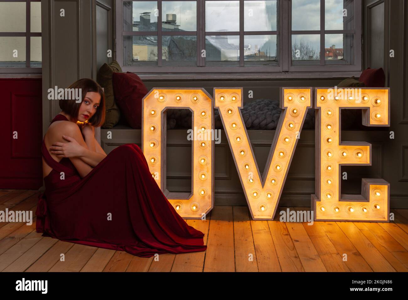 A woman with crossed arms in a red dress making letter L sitting in ...