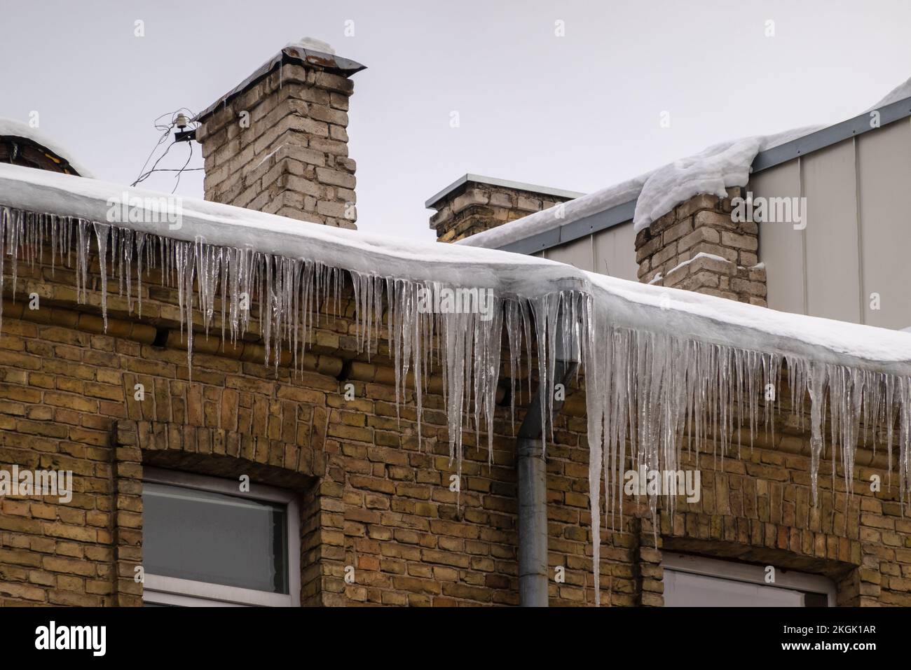 Sharp icicles hanging on the edge of the roof. Melting snow forms icicle Stock Photo - Alamy