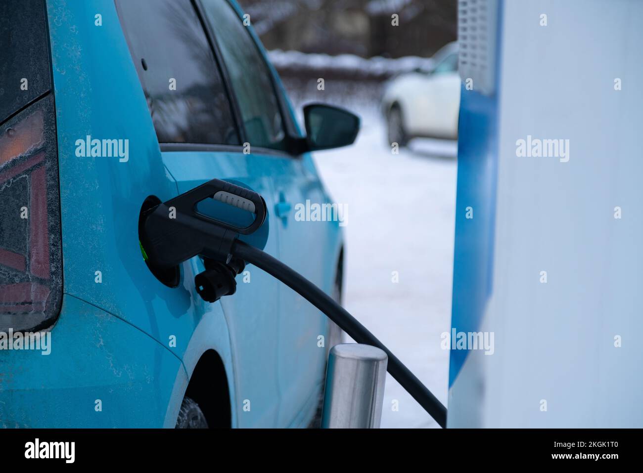 Charger plug inserted in electric car on snowy winter background. Green ...