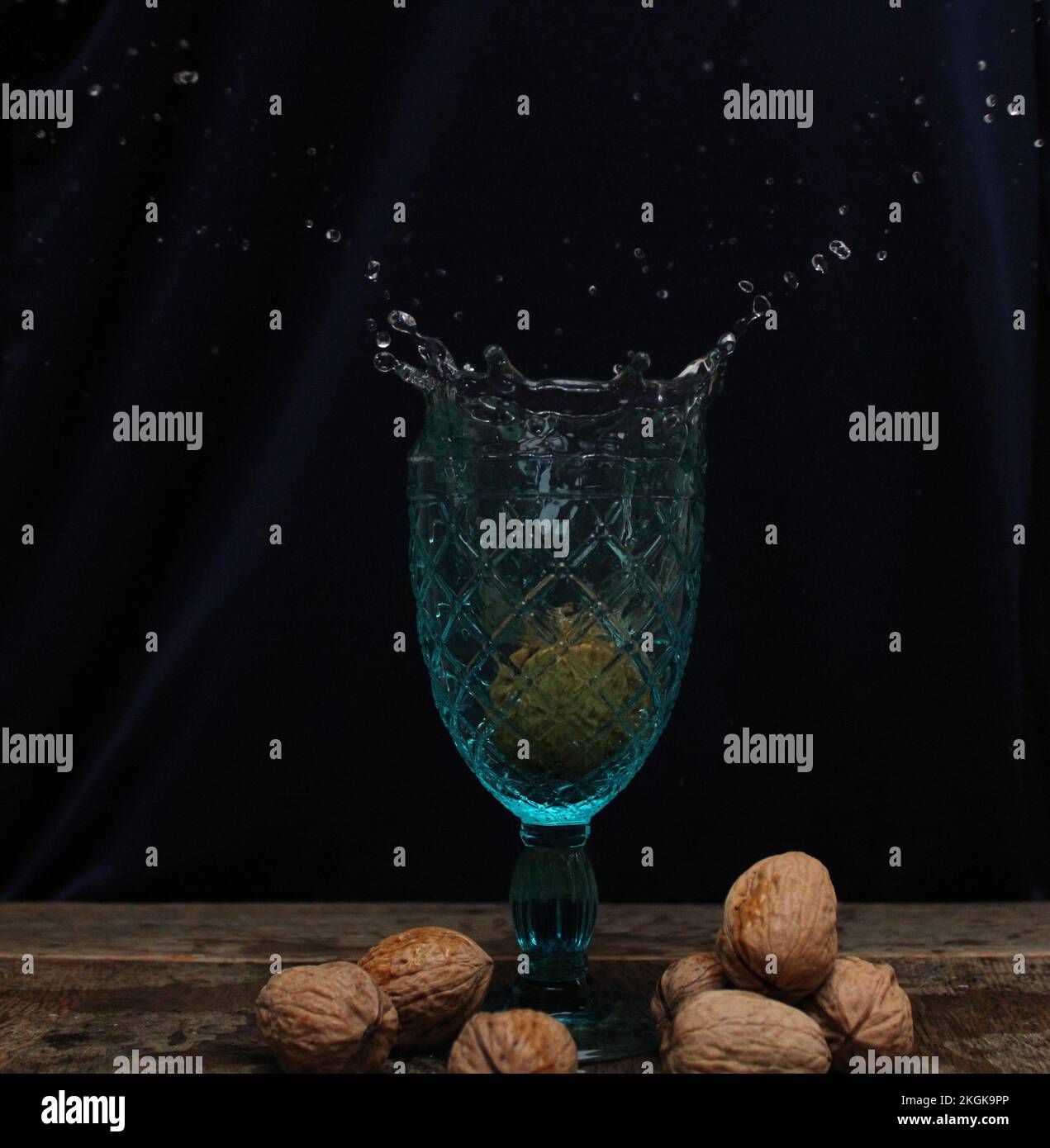 A splash of water in a glass with a walnut Stock Photo - Alamy
