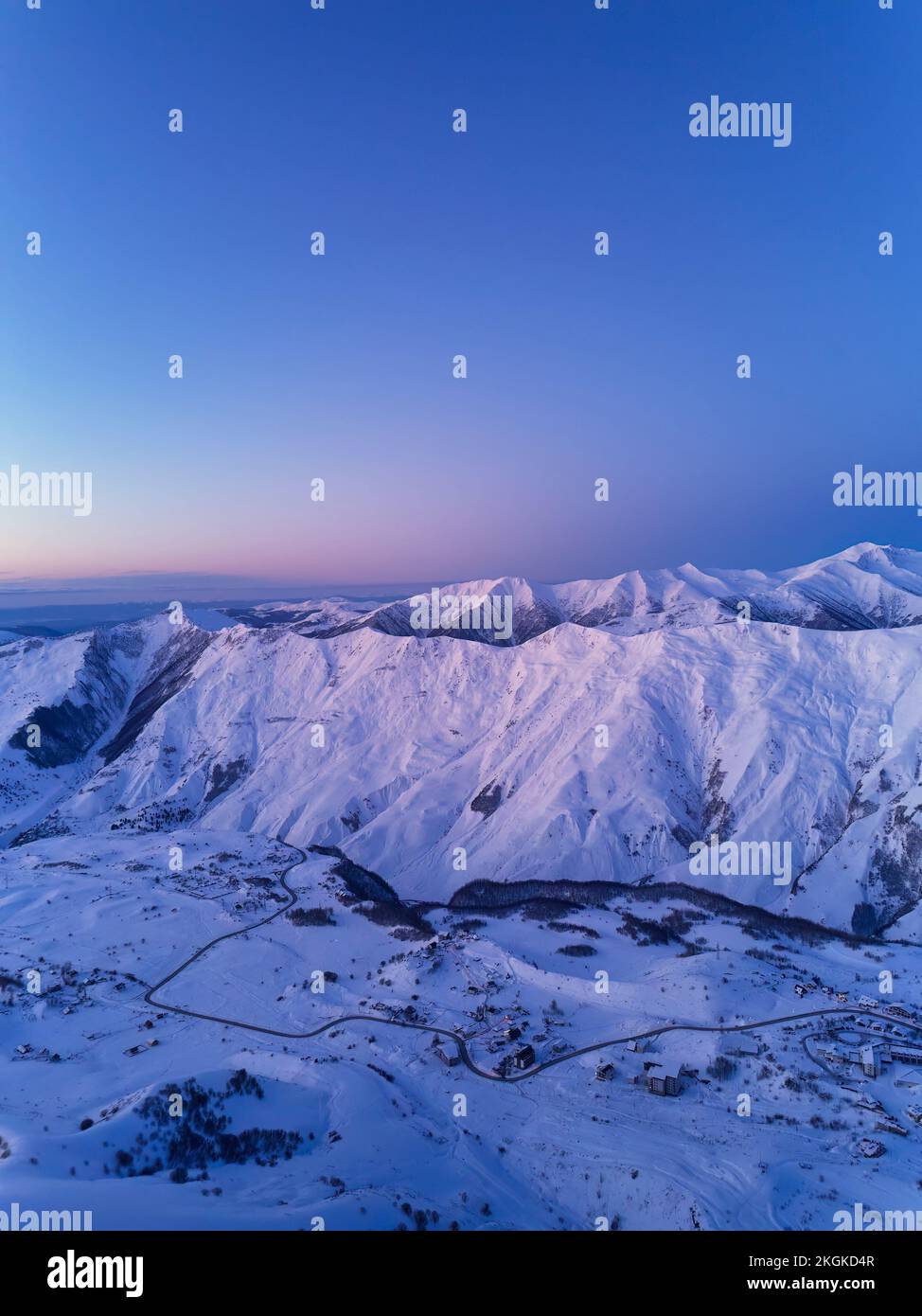 Aerial of snowy mountain range on winter sunrise at ski resort ...