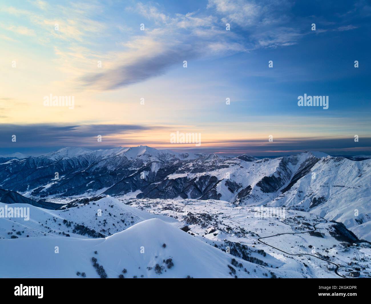 Wide aerial panorama of snowy mountain ridge at ski resort village on ...