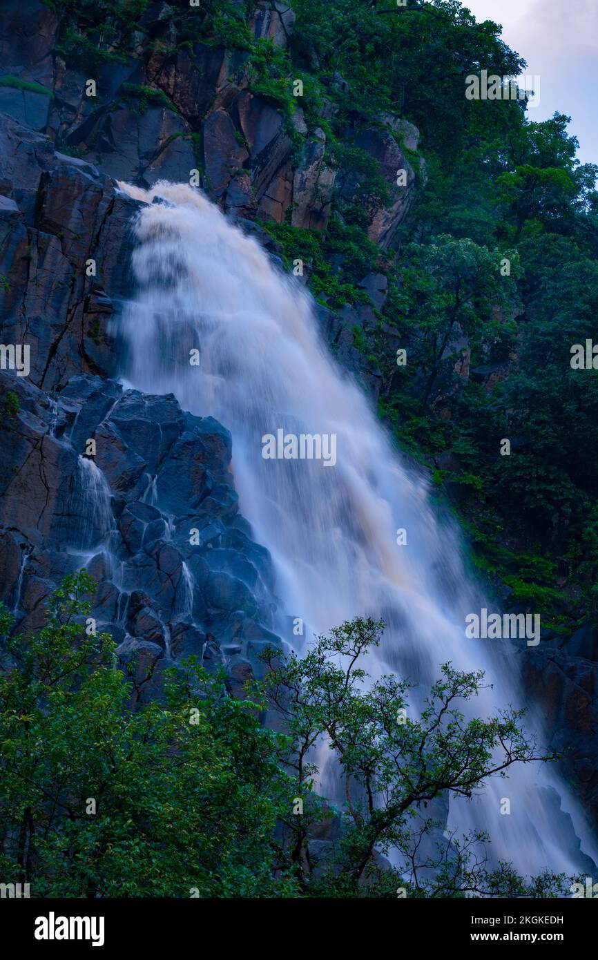 A raging waterfalls surrounded by trees and rocks Stock Photo - Alamy
