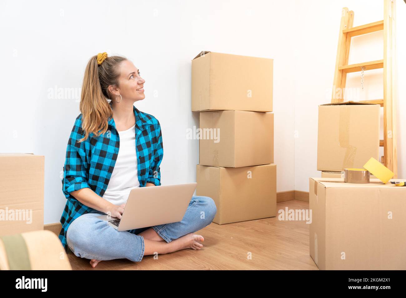 Young happy woman sitting on the floor with many boxes, working with ...