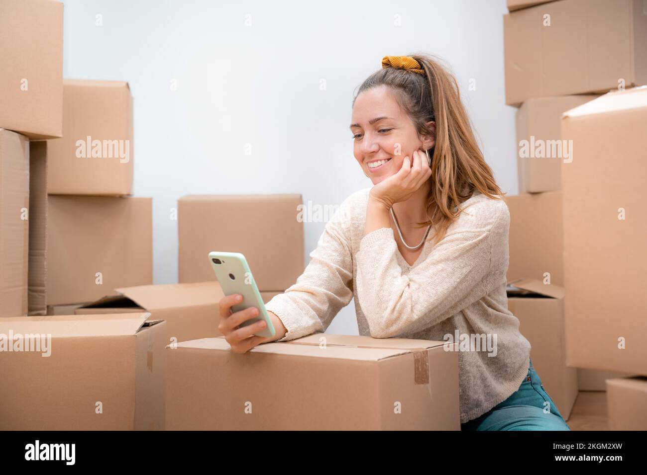 Beautiful girl with cardboard boxes unpacking in new home - Video call ...