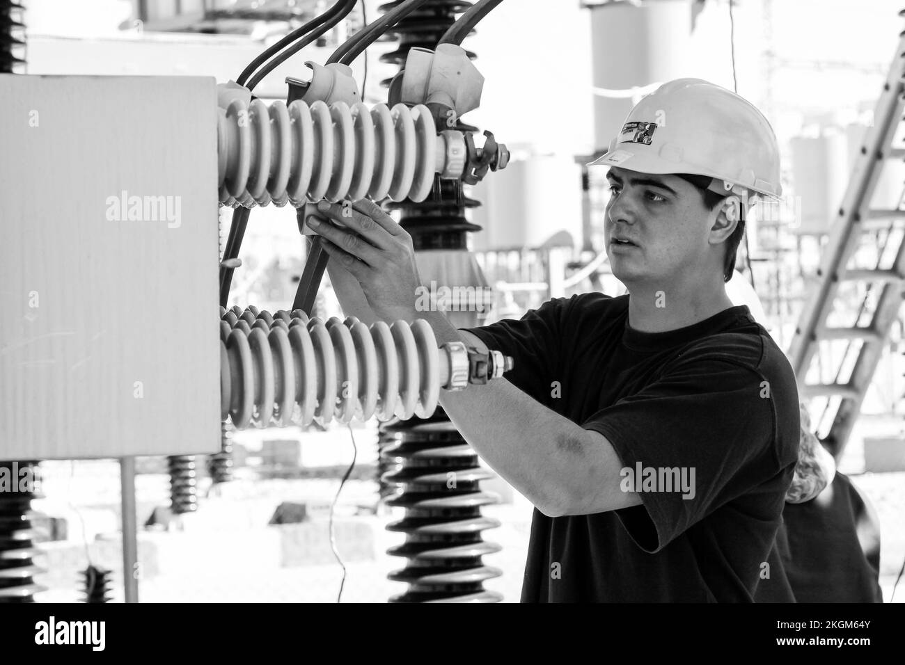 The grayscale portrait of an electrician working on high-voltage power ...
