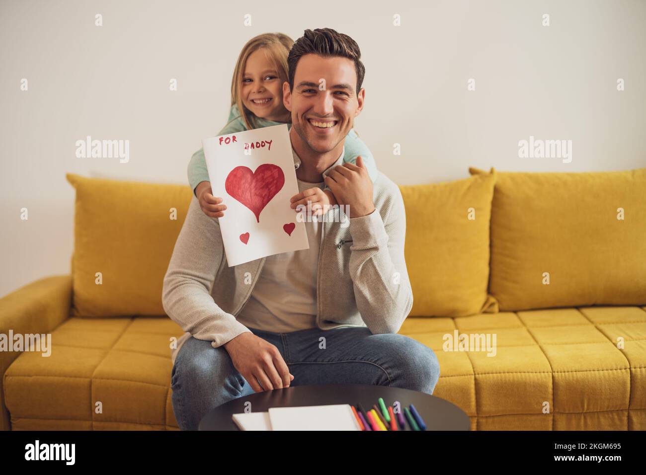 Happy father and daughter holding greeting card with heart shapes and ...