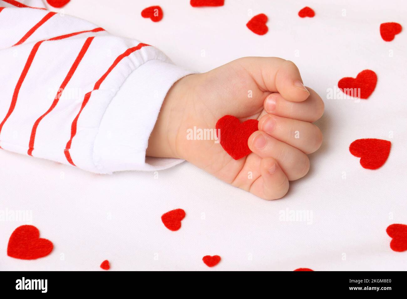 An Infant hand holding a red felt heart Stock Photo - Alamy