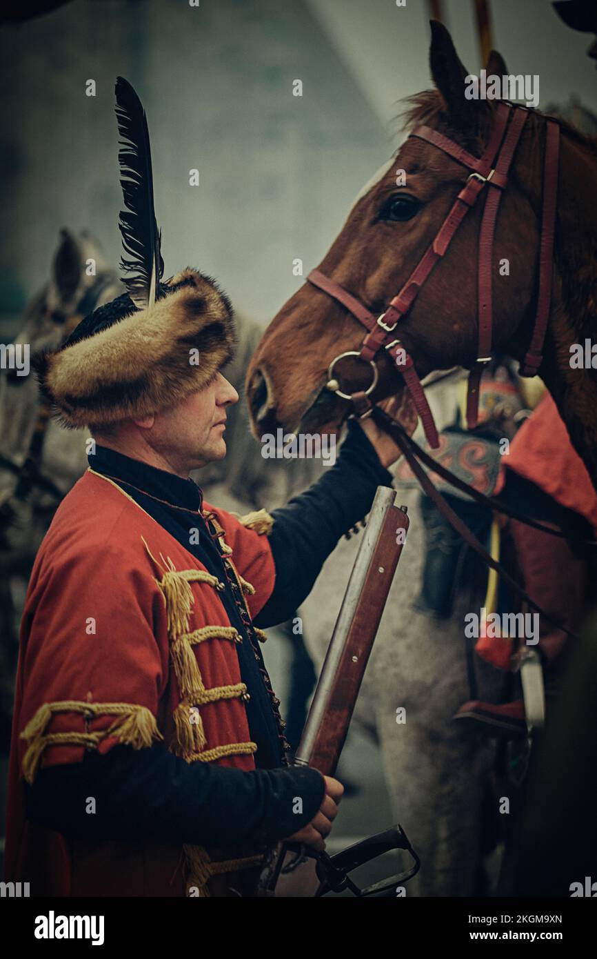A vertical of a man in traditional Polish clothes holding a riffle on ...
