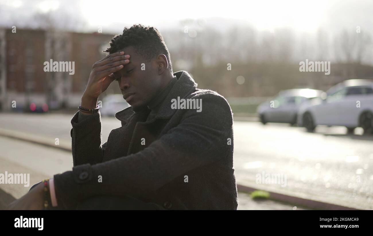 Worried black man suffering alone in emotional pain outside in city ...