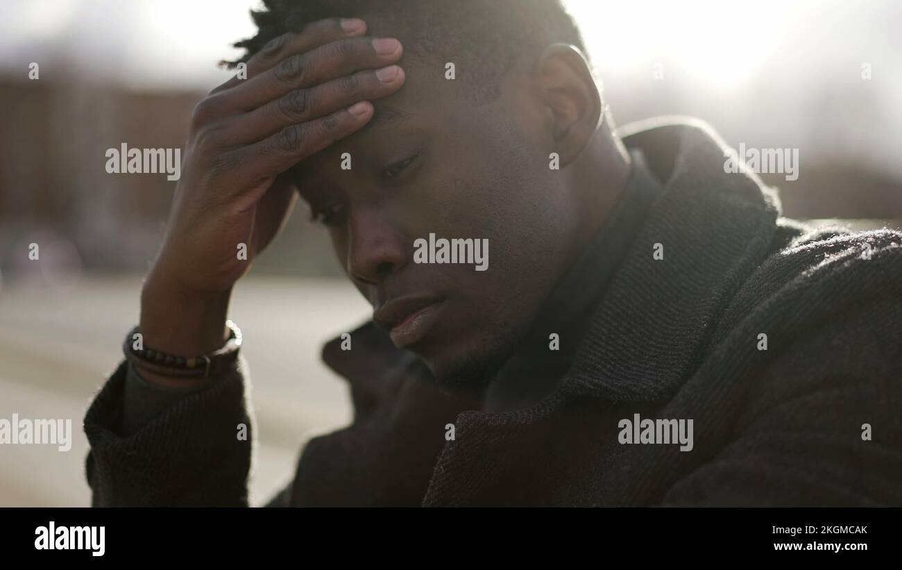 Worried black man suffering alone in emotional pain outside in city ...