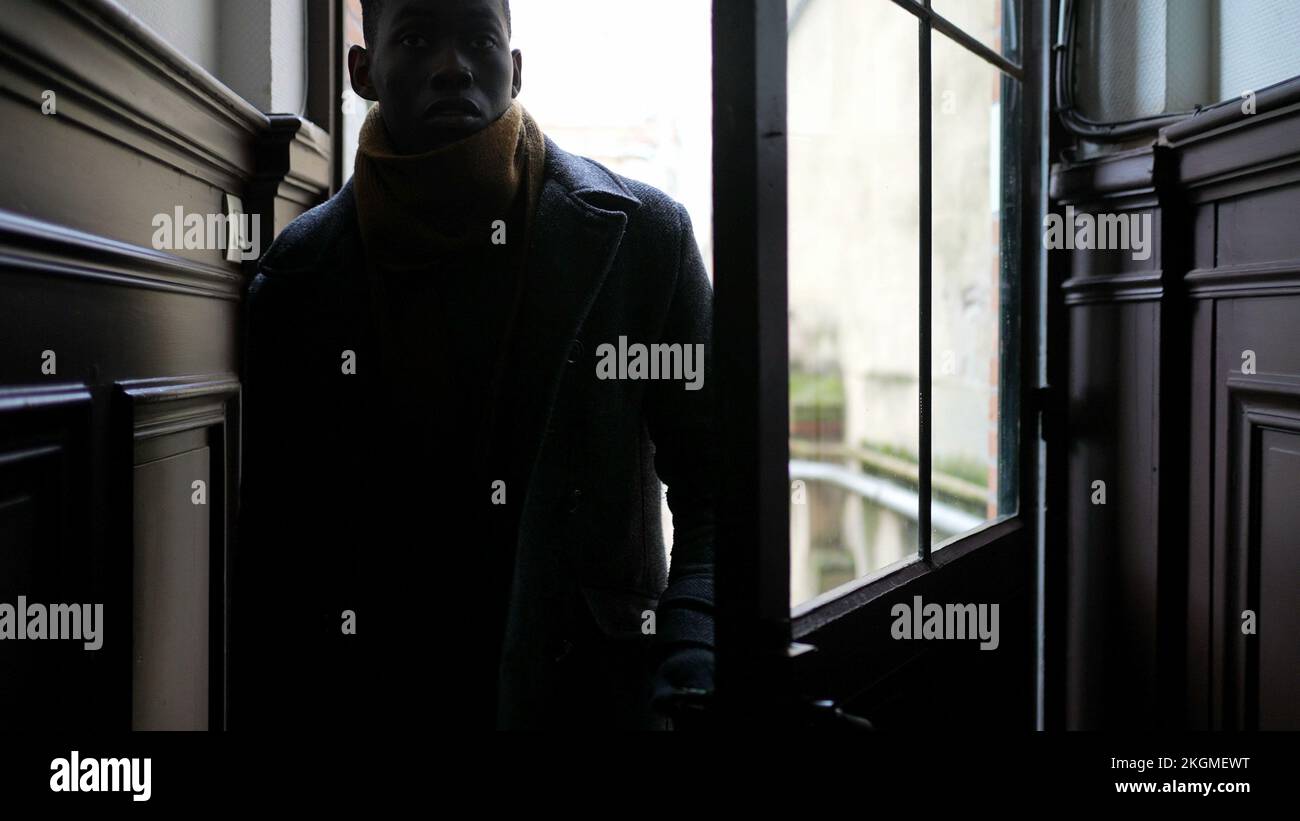 Young black man stepping outside walking through corridor, person ...