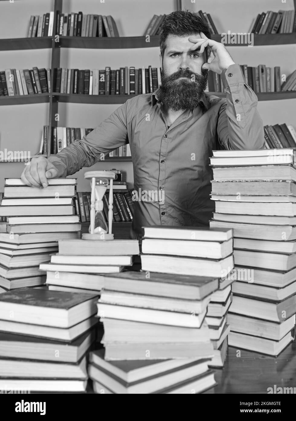 Librarian concept. Man on thoughtful face stands between piles of books ...
